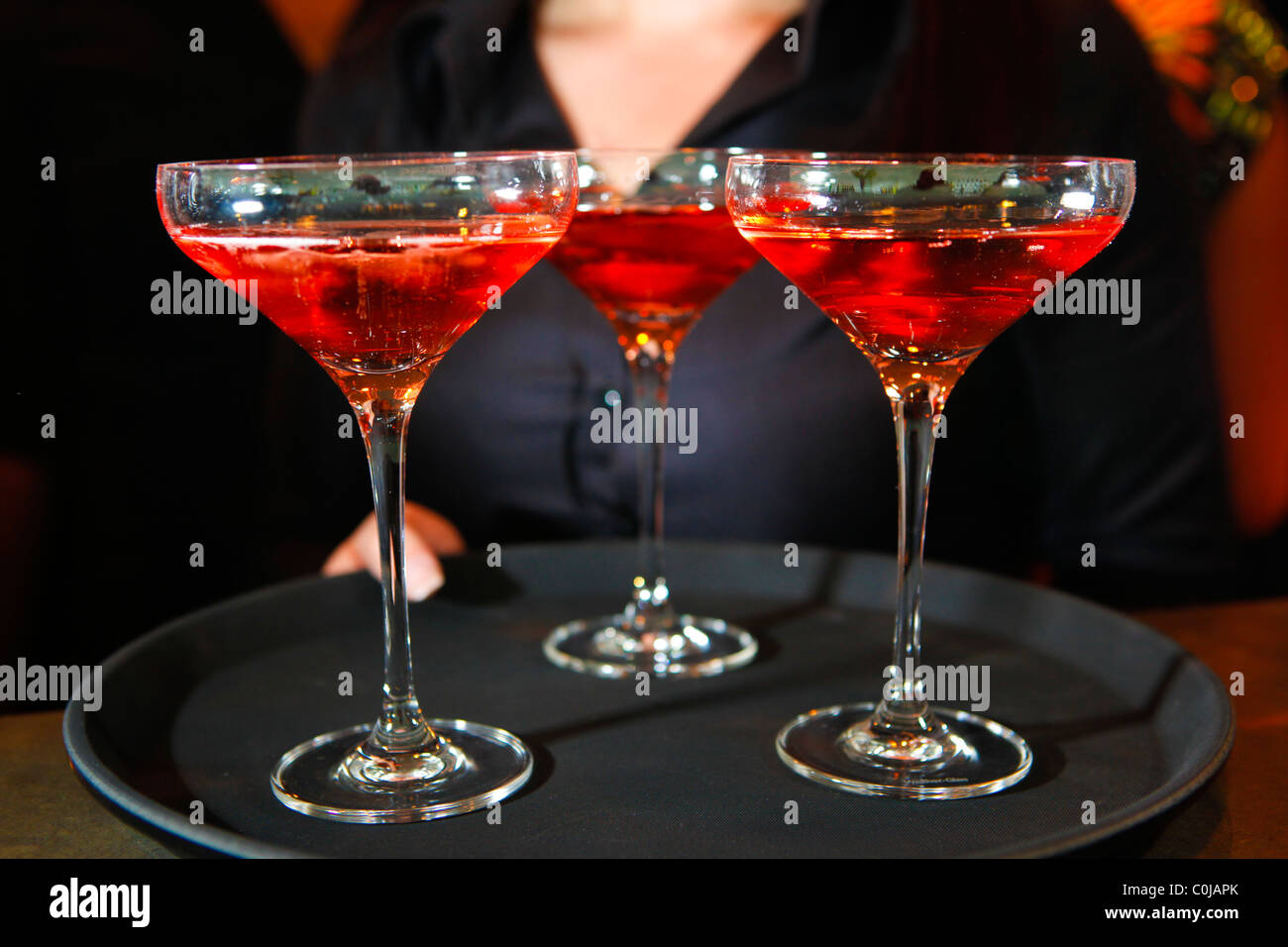 A Waitress Holding A Tray Of Pink Champagne Glasses In A Bar Stock