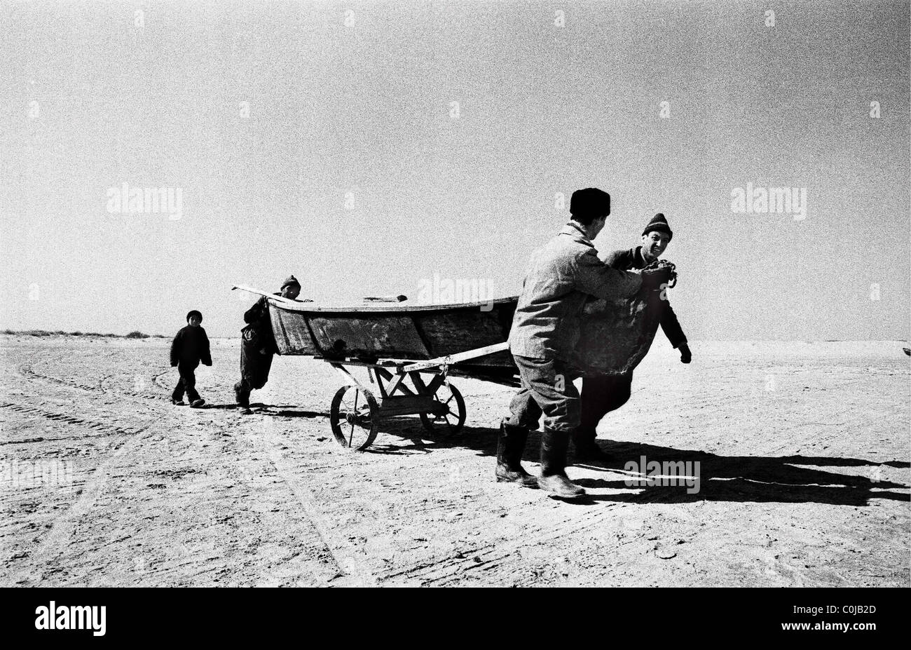 Men push a fishing boat across the former sea-bed of the Aral Sea to ...