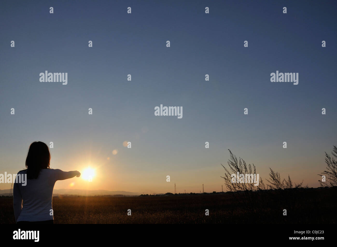 Young woman pointing at sun Stock Photo - Alamy