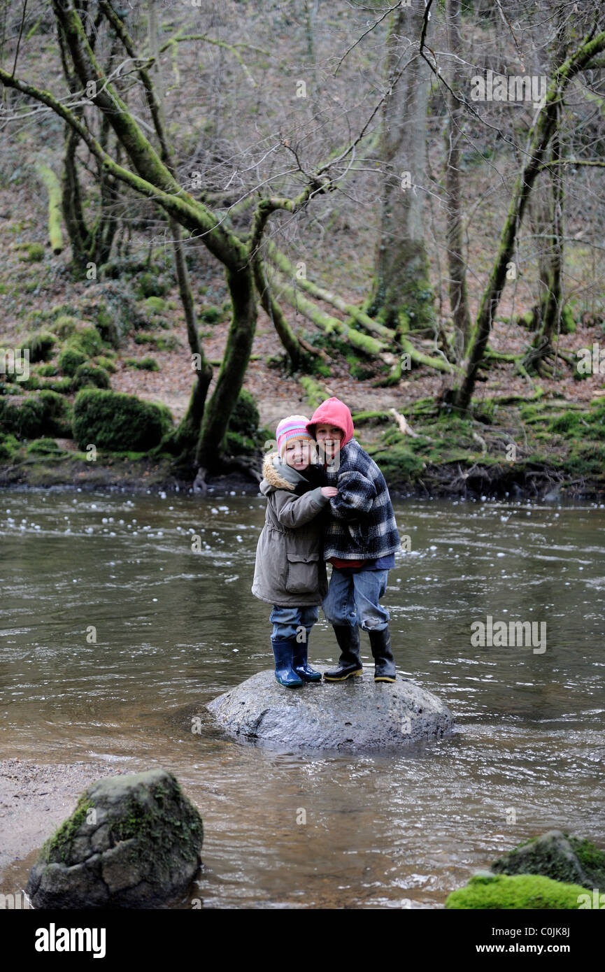 Stock photo of two children playing on a boulder in a stream on a ...