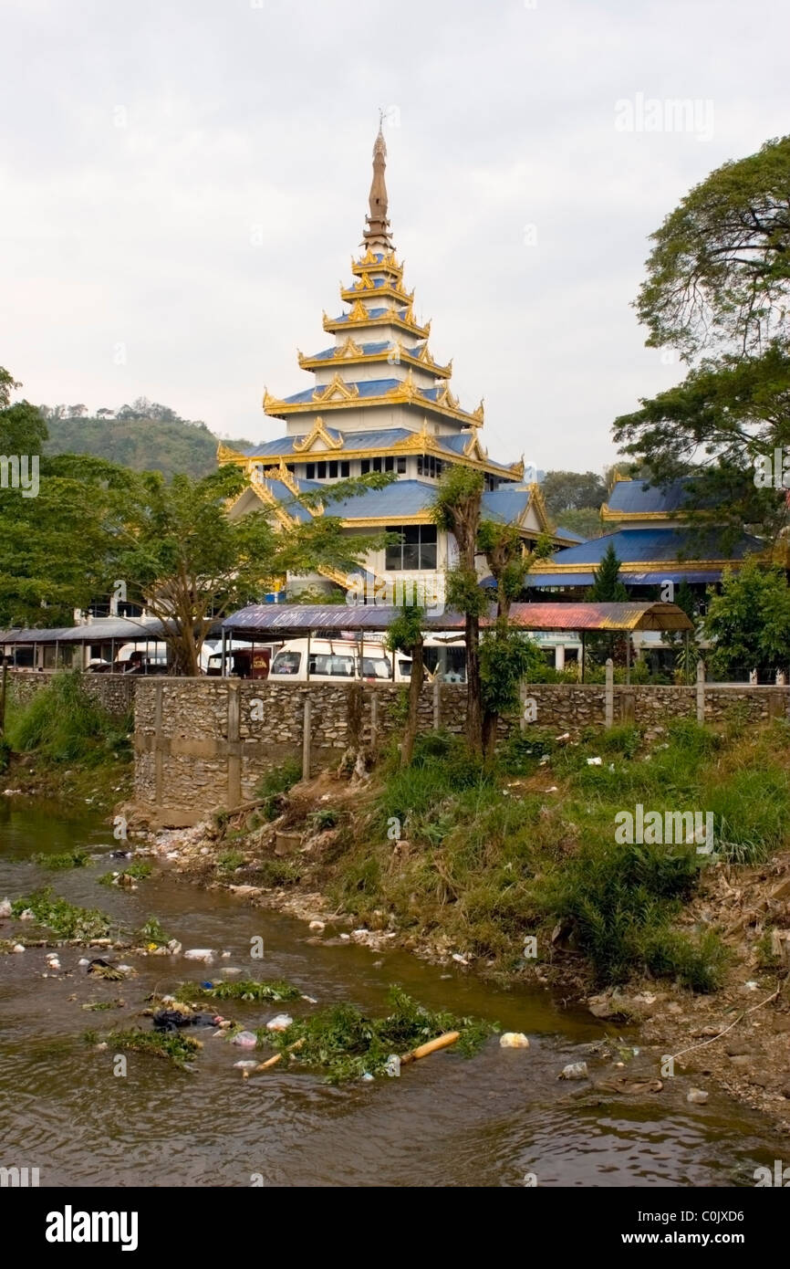 A Burmese style Buddhist temple overlooks a dirty and polluted river in ...