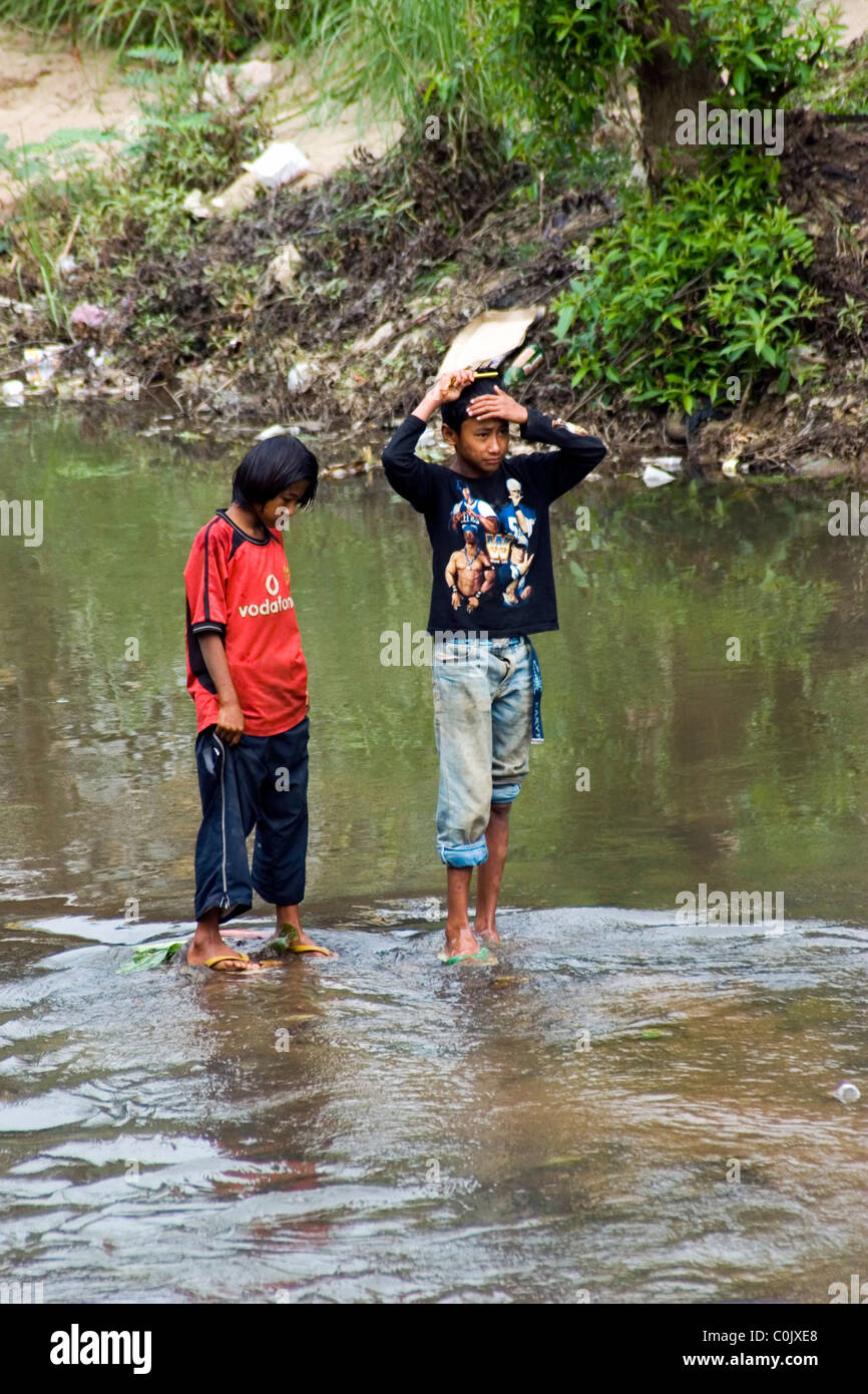 Two Burmese teenage boys are bathing in a dirty and polluted river in ...