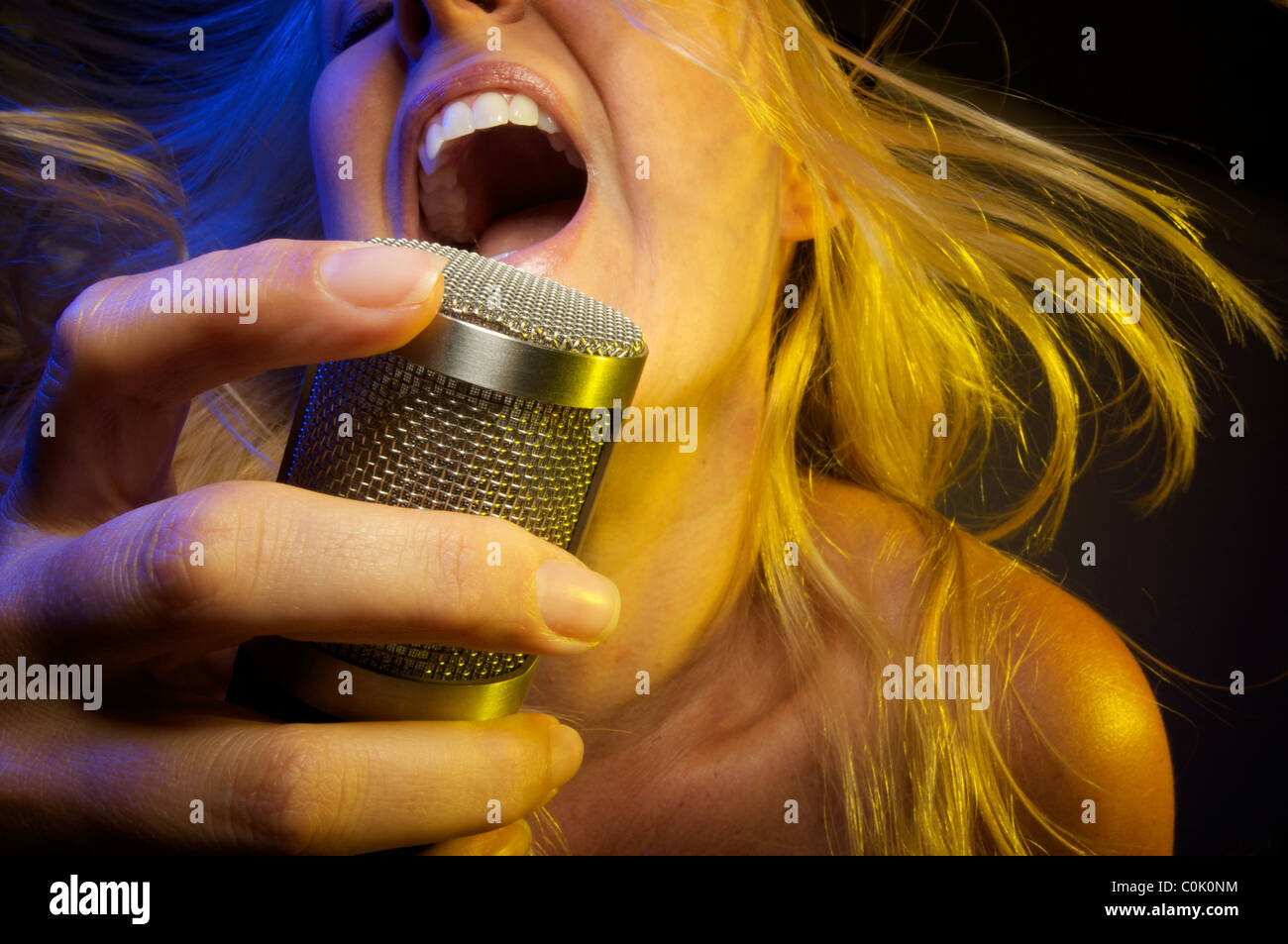 Blonde Woman with Microphone Sings with Passion Stock Photo - Alamy