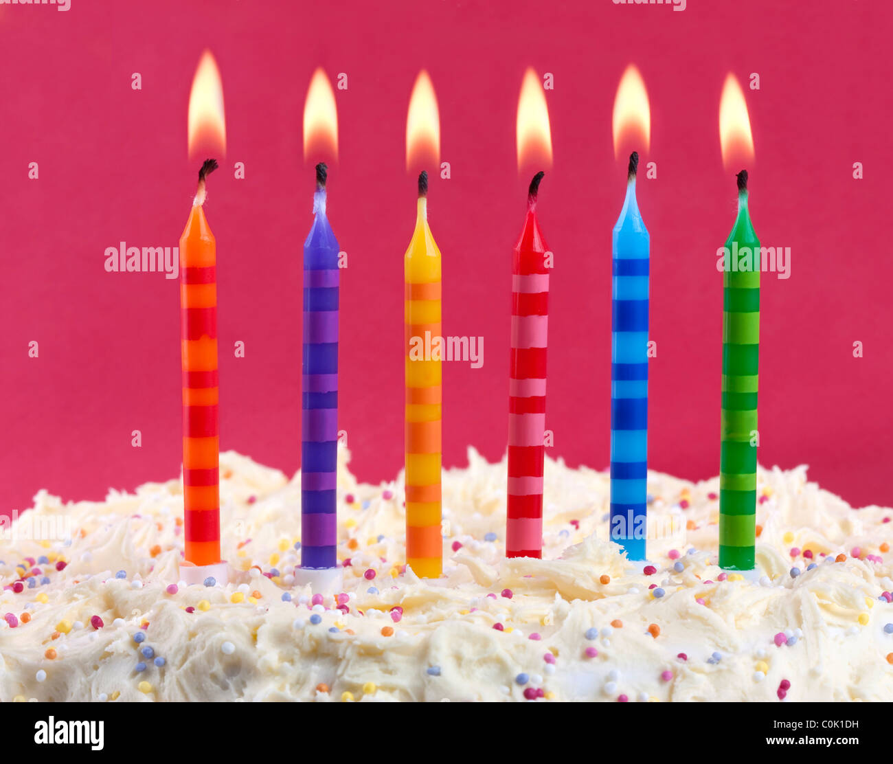 birthday cake with 6 coloured candles on a red background Stock Photo ...