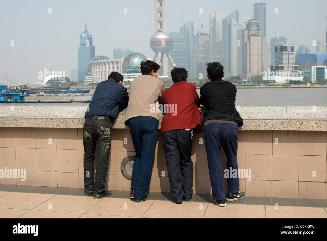 Four young Chinese men on the Bund, Shanghai, facing Pudong and the ...
