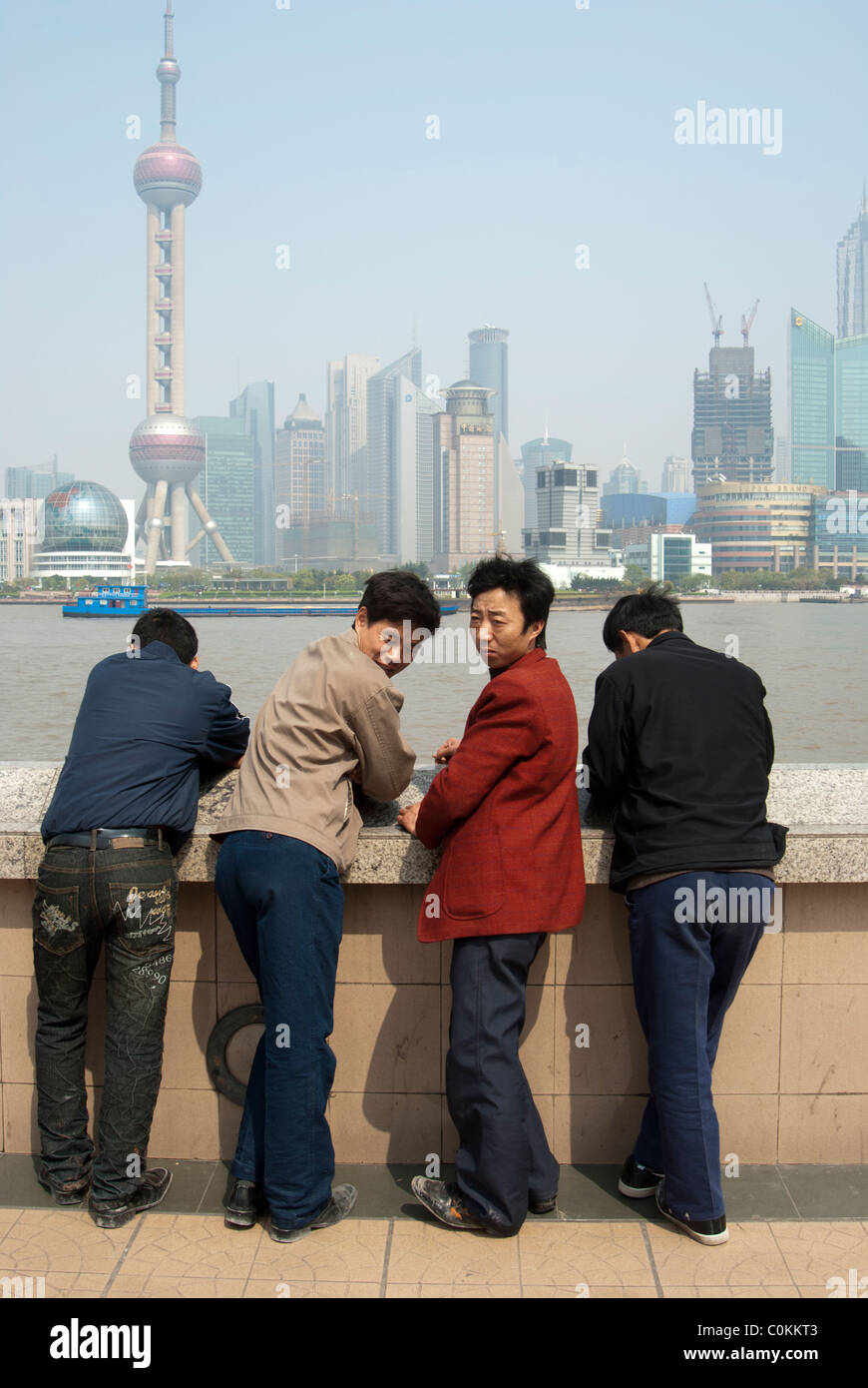 Four young Chinese men on the Bund, Shanghai, facing Pudong and the ...