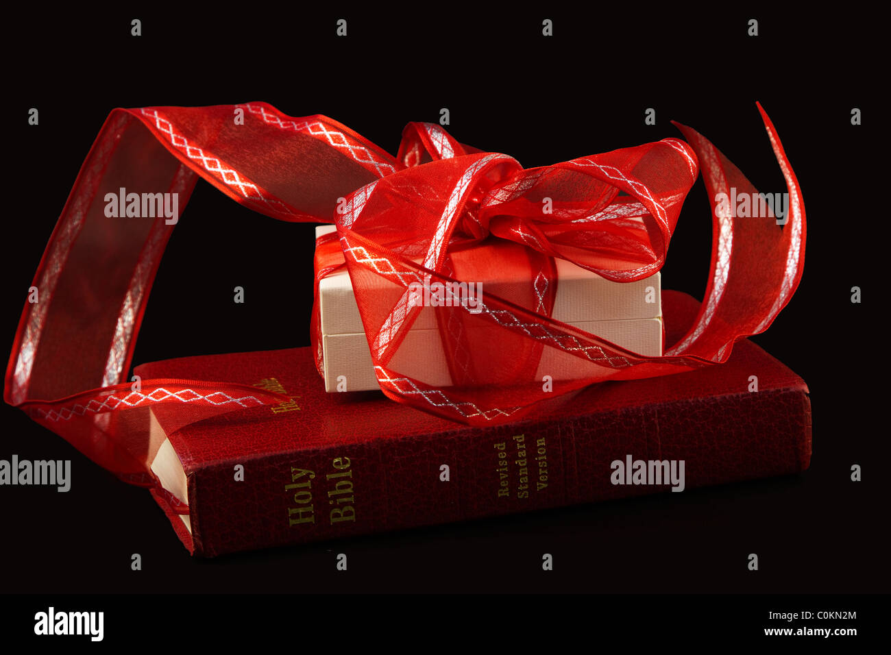 Red Bible with white gift wrapped in red ribbon on simple, black ...