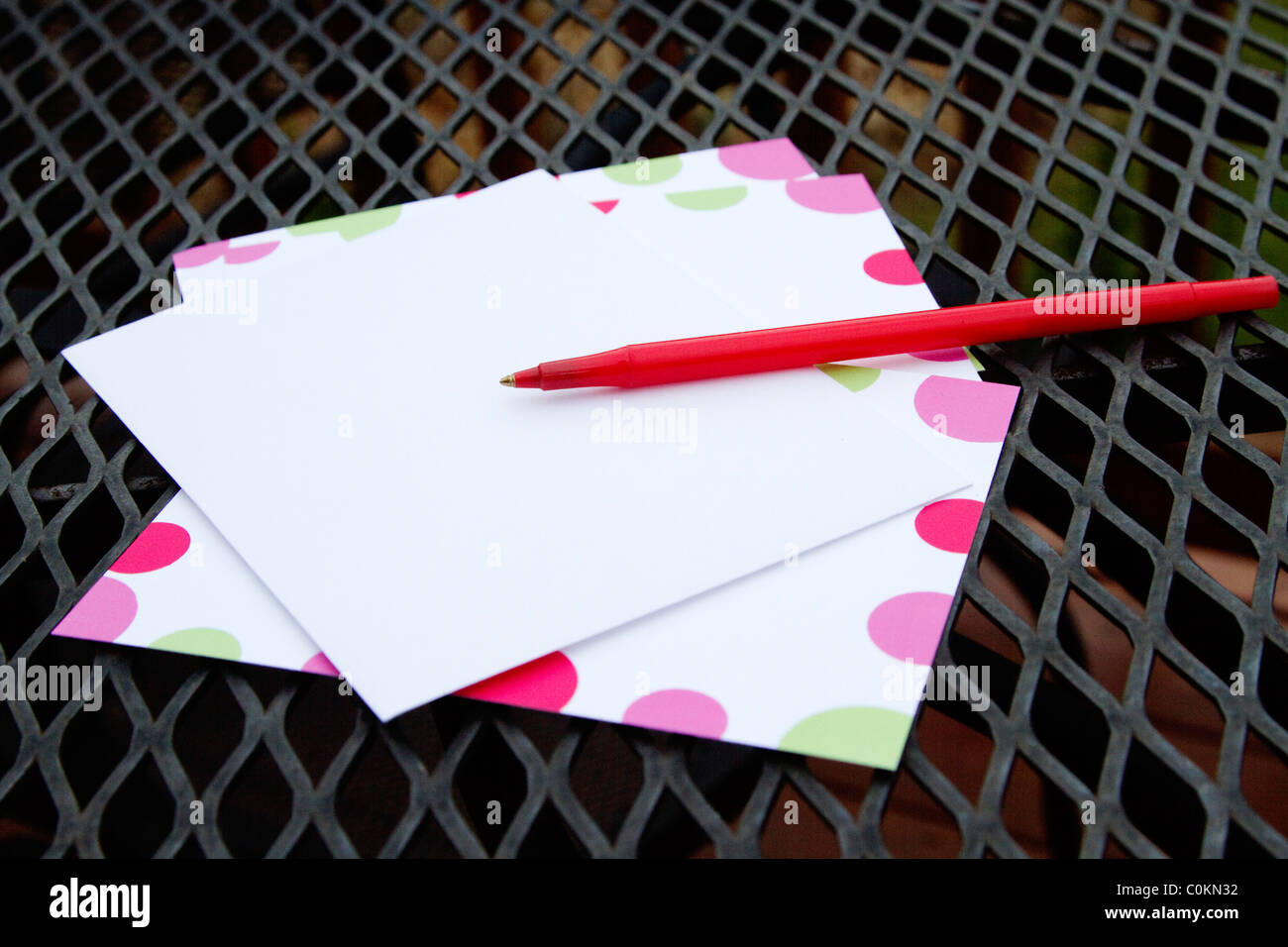 Red pen and note paper placed on black wrought iron patio table top ...