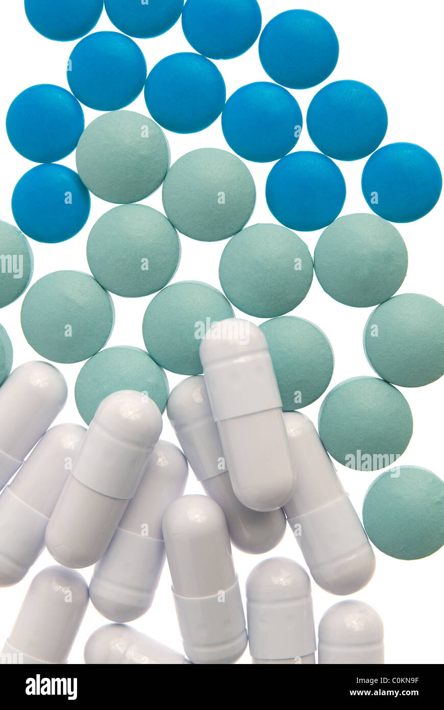 Macro view of white capsule, green and blue pills on blue background ...