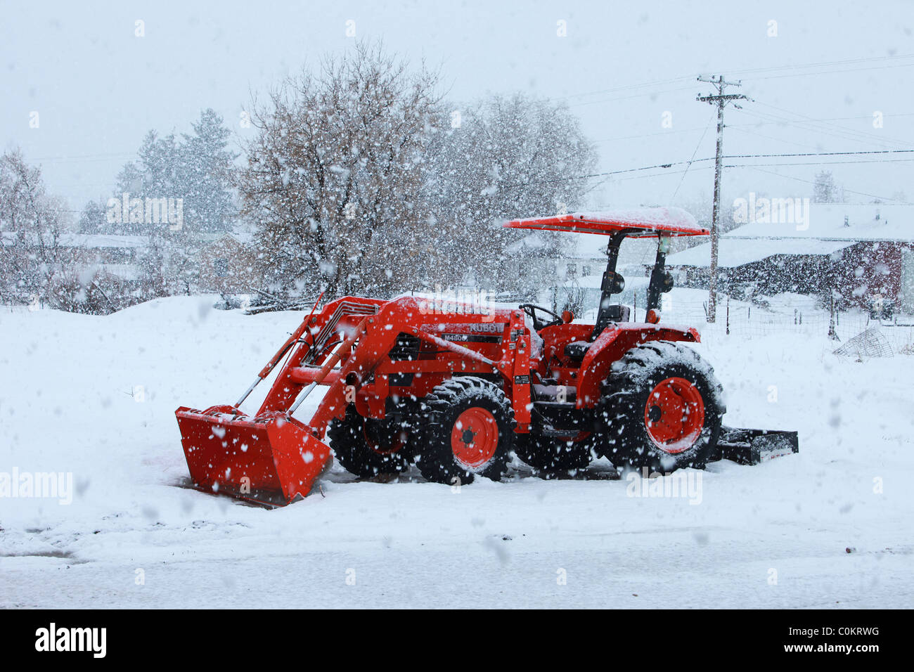 Snow blizzard on bright orange farm tractor. Heavy snow falling Stock ...