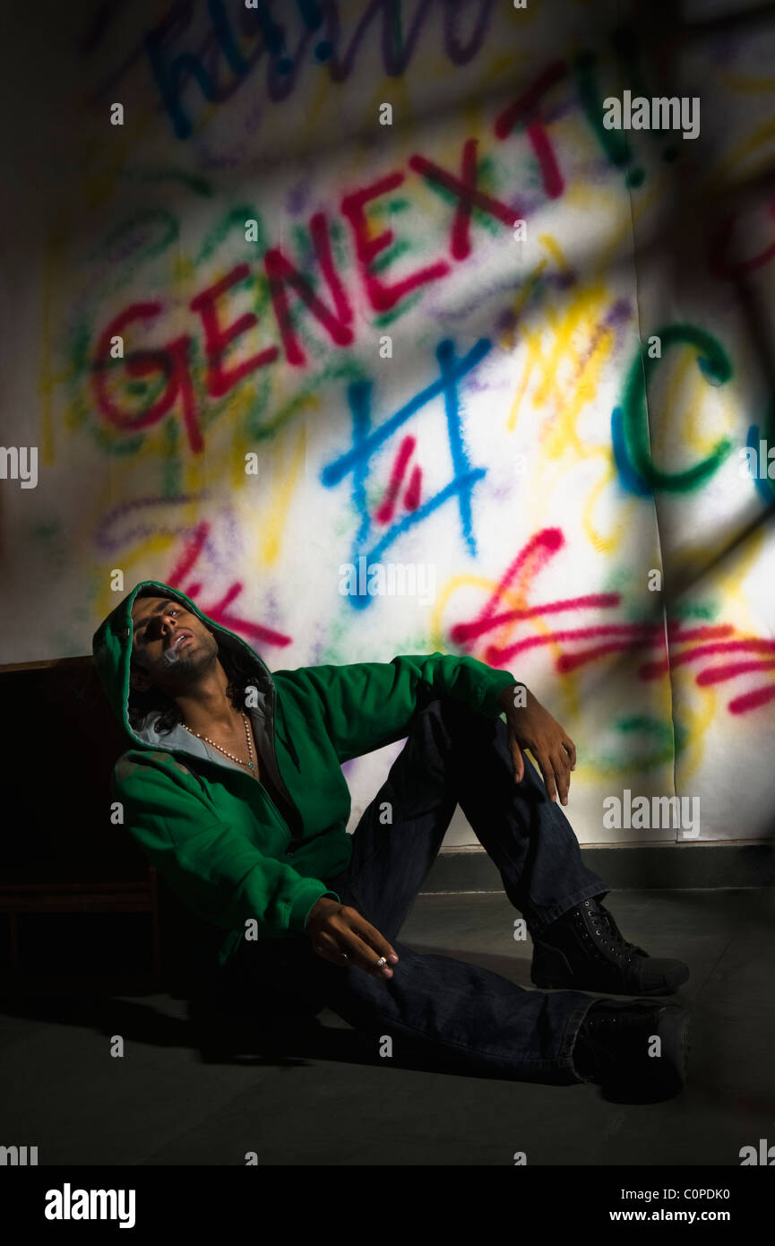 Man smoking in front of a graffiti covered wall Stock Photo - Alamy
