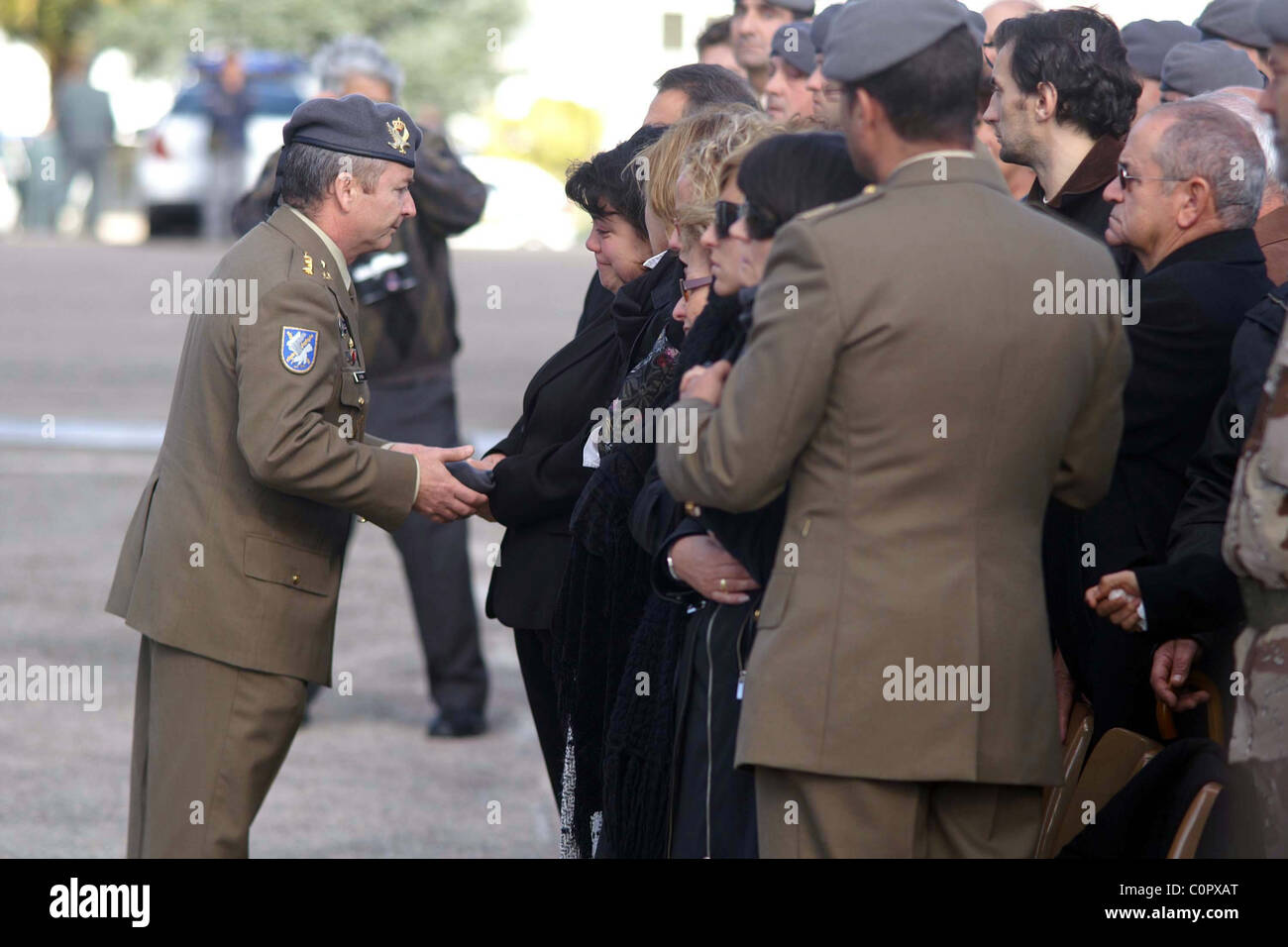 A high ranking military officer talks to mourners at a military funeral ...