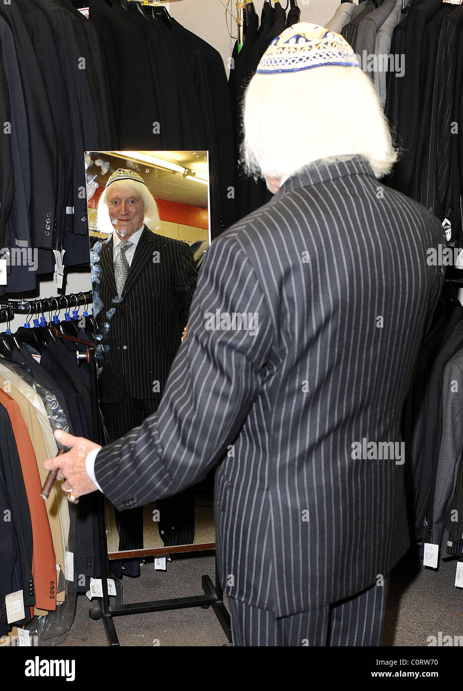 Sir Jimmy Savile tries on a suit at Warren Gold at Gold's Factory ...