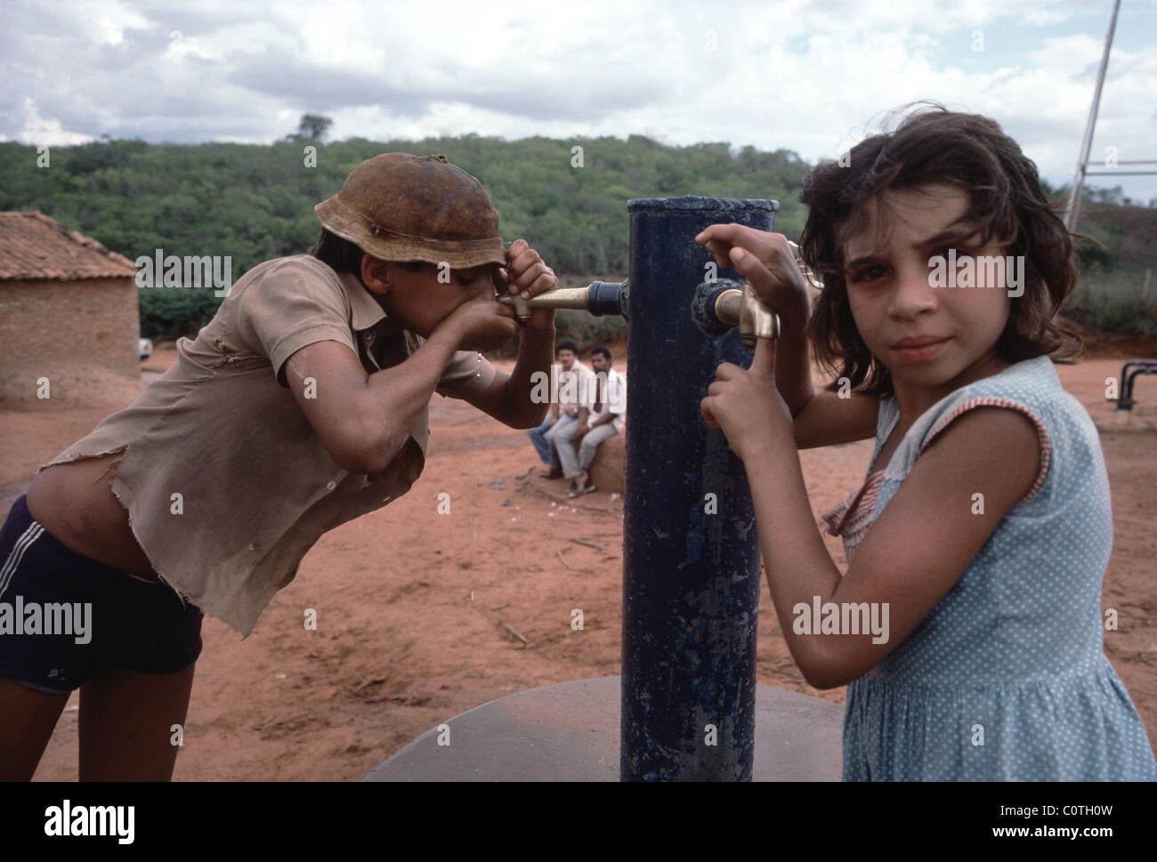 Two children drink water from a community tap in a drought prone area ...