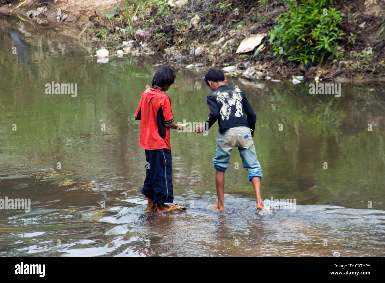 Two Burmese teenage boys are bathing in a dirty and polluted river in ...
