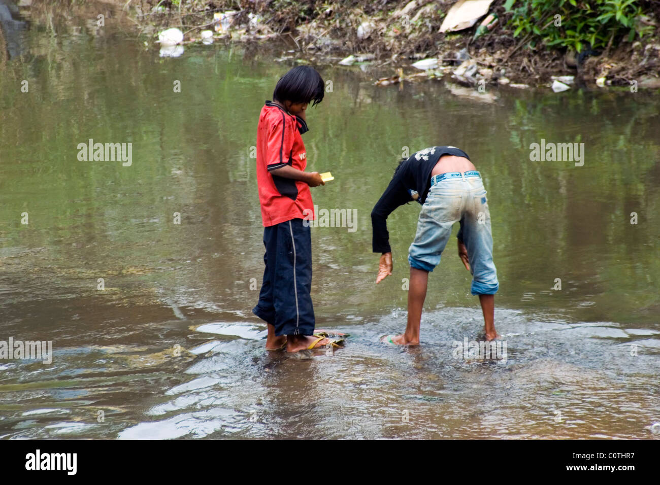 Two Burmese teenage boys are bathing in a dirty and polluted river in ...