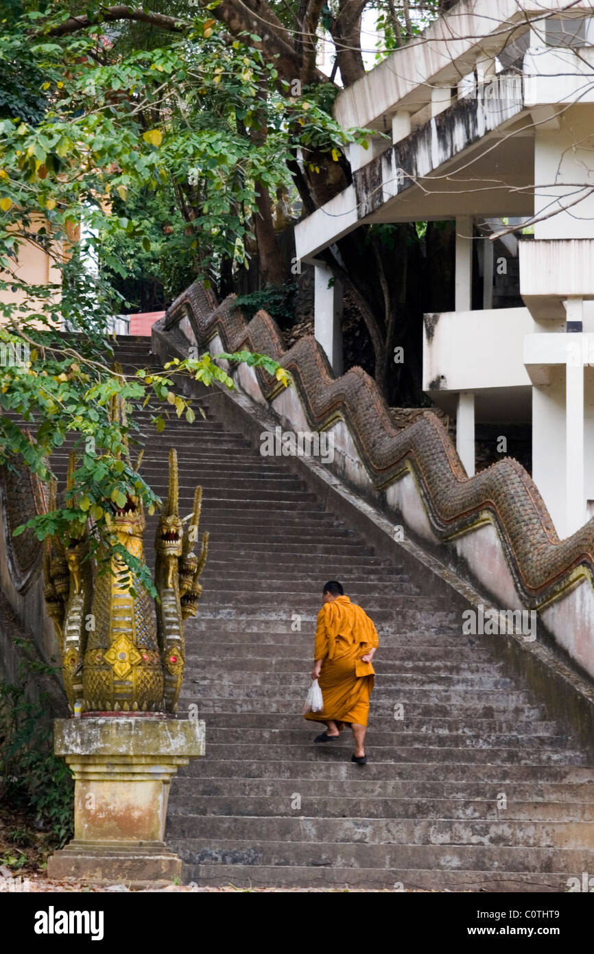 A Buddhist monk is climbing a long and steep stone stairway leading to ...