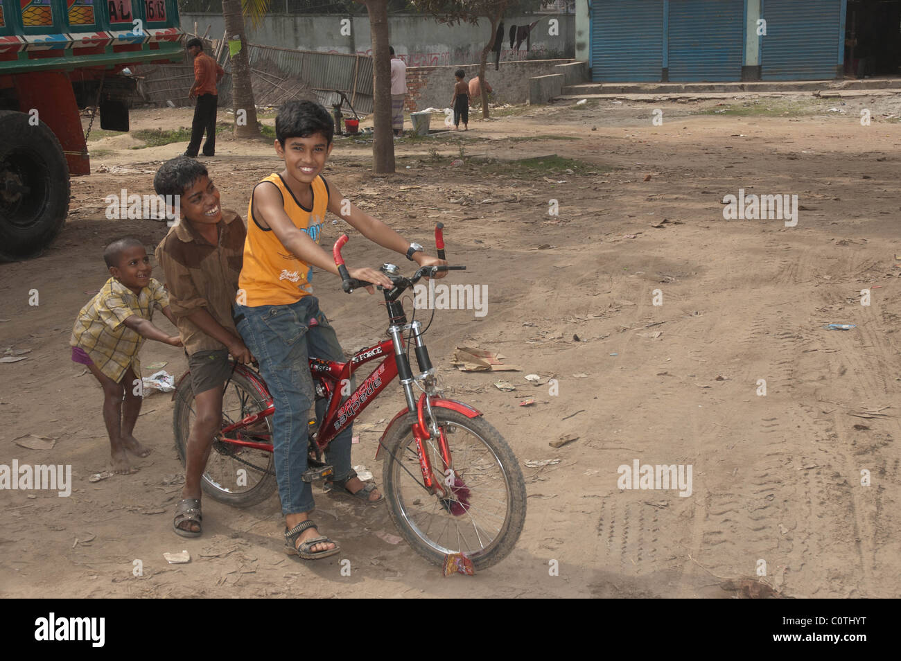 Three young boys playing on a red bicycle in Bangladesh Stock Photo - Alamy