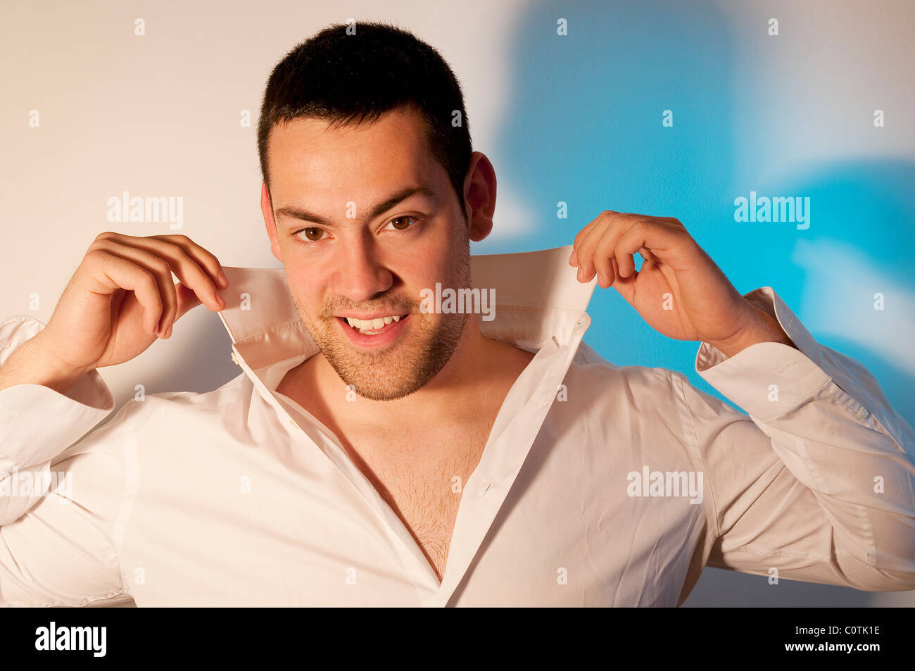 Young man stretching his shirt collar, smiling and looking at the ...