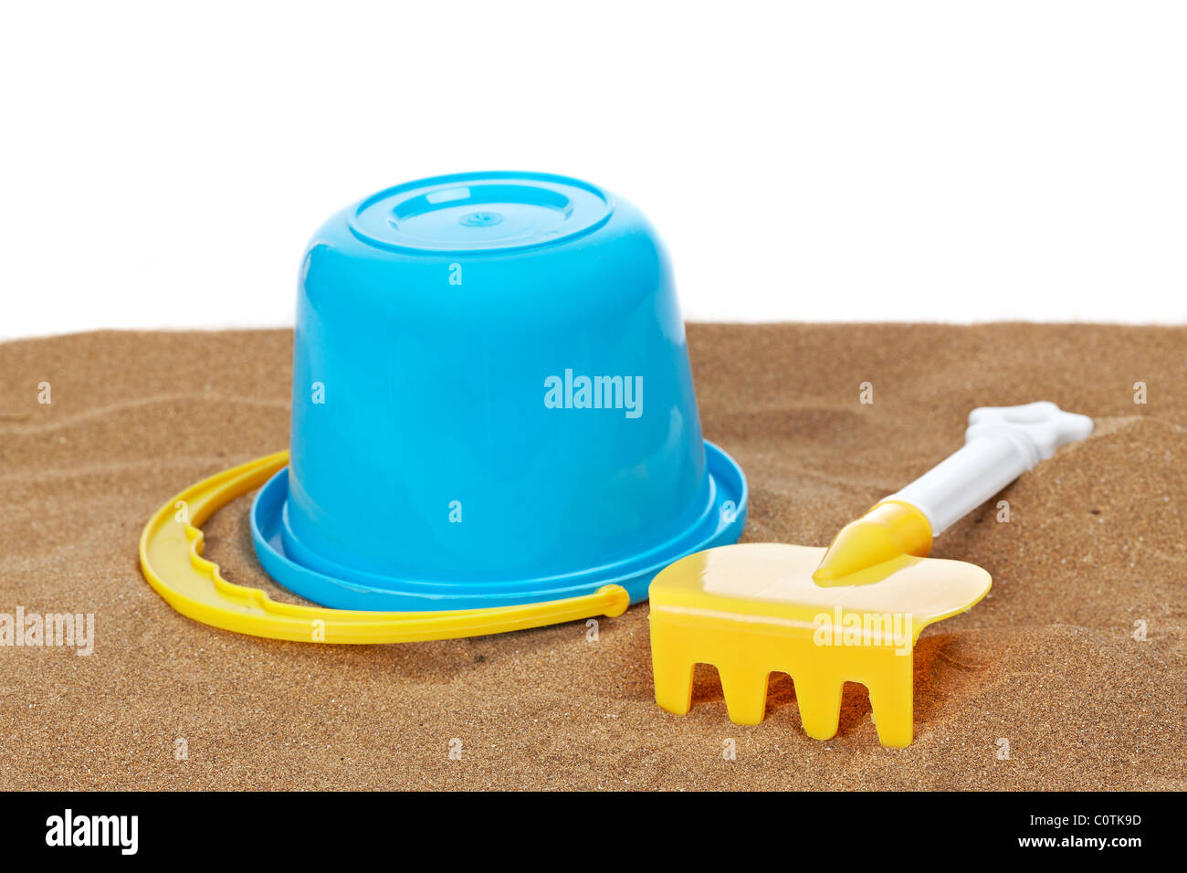 Bucket full and rake on the sand with copy space on a white background ...