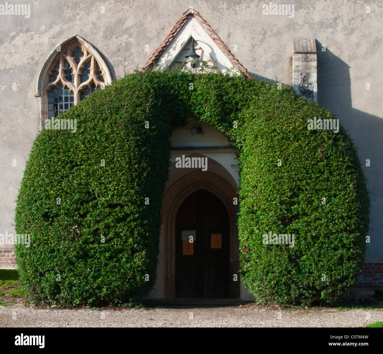 Church door with a hedge growing around it Stock Photo - Alamy