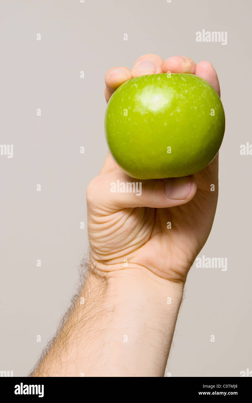 Apple held by hand isolated on a gray/white background with space for ...
