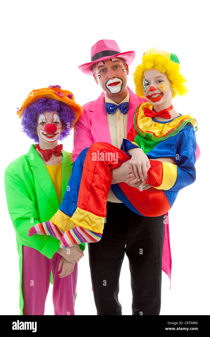 Three people dressed up as colorful funny clowns over white background ...
