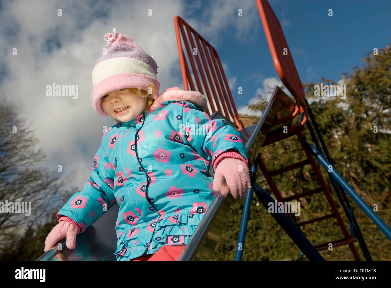 Preschool female child sliding down playground slide Stock Photo - Alamy