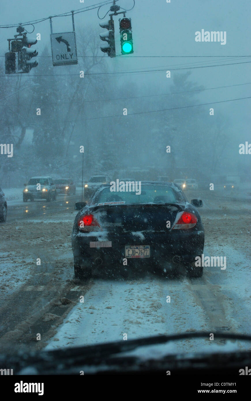 Auto crosses intersection cautiously in snow storm Stock Photo - Alamy