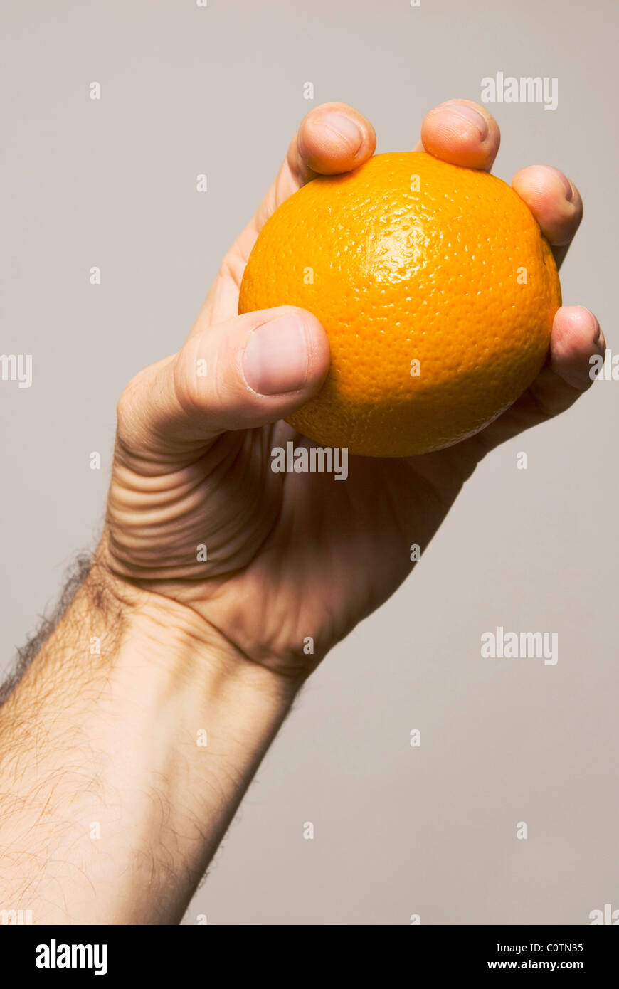 Hand grasping an orange on a neutral with space for text or cutout ...