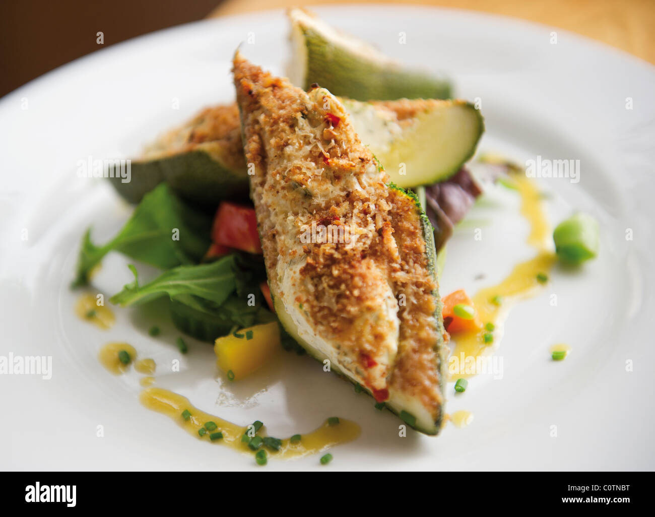 A starter of baked courgette filled with soft cream cheese scented with ...