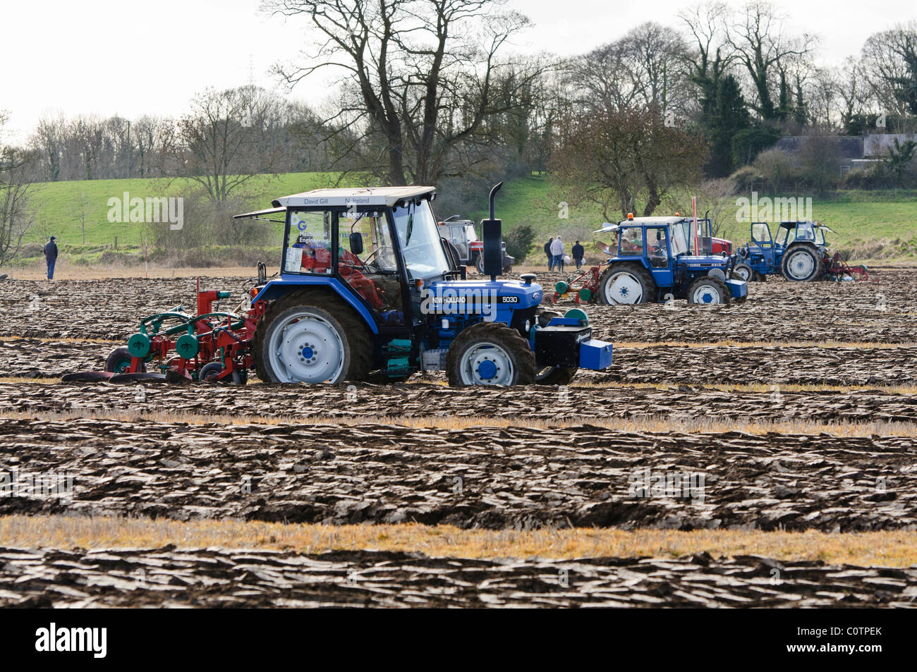 Farmers using a modern tractors to plough a field Stock Photo - Alamy