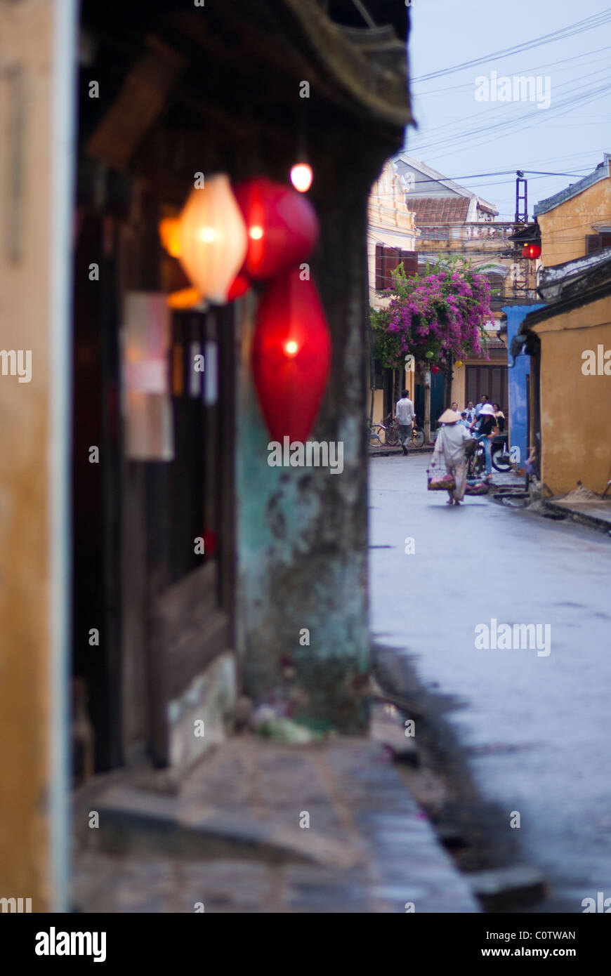 Hoi Ann, street view in the early evening with lanterns and a worker ...