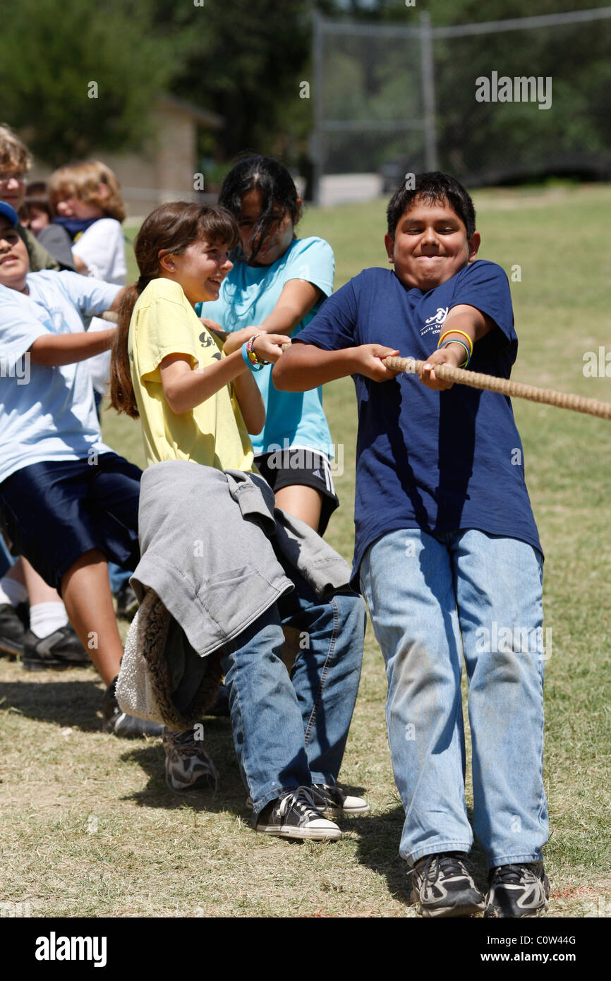 Fifth-grade boys and girls pull on rope during tug-of-war at elementary ...
