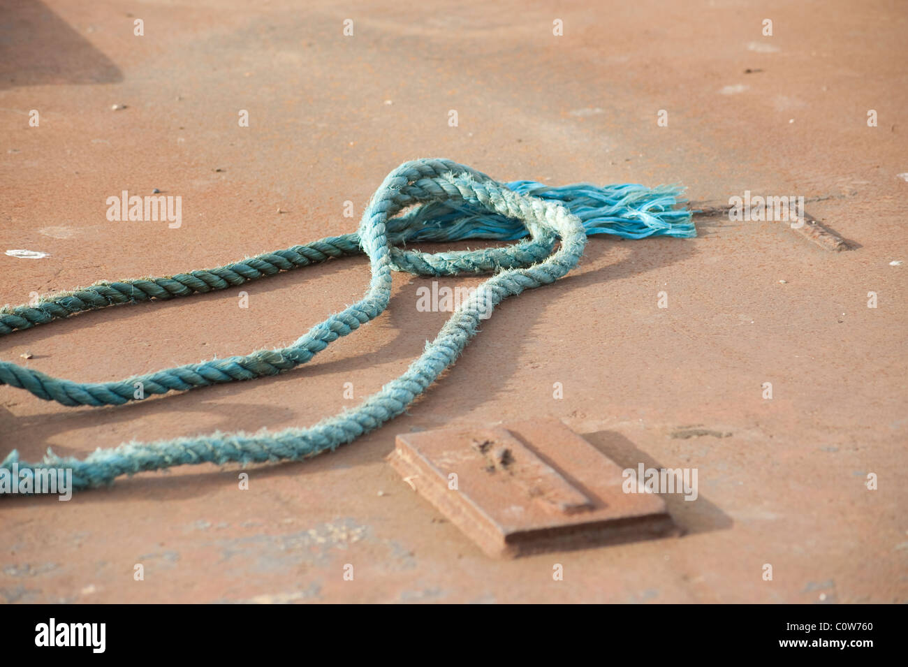 Frayed blue rope on pale red deck Stock Photo - Alamy