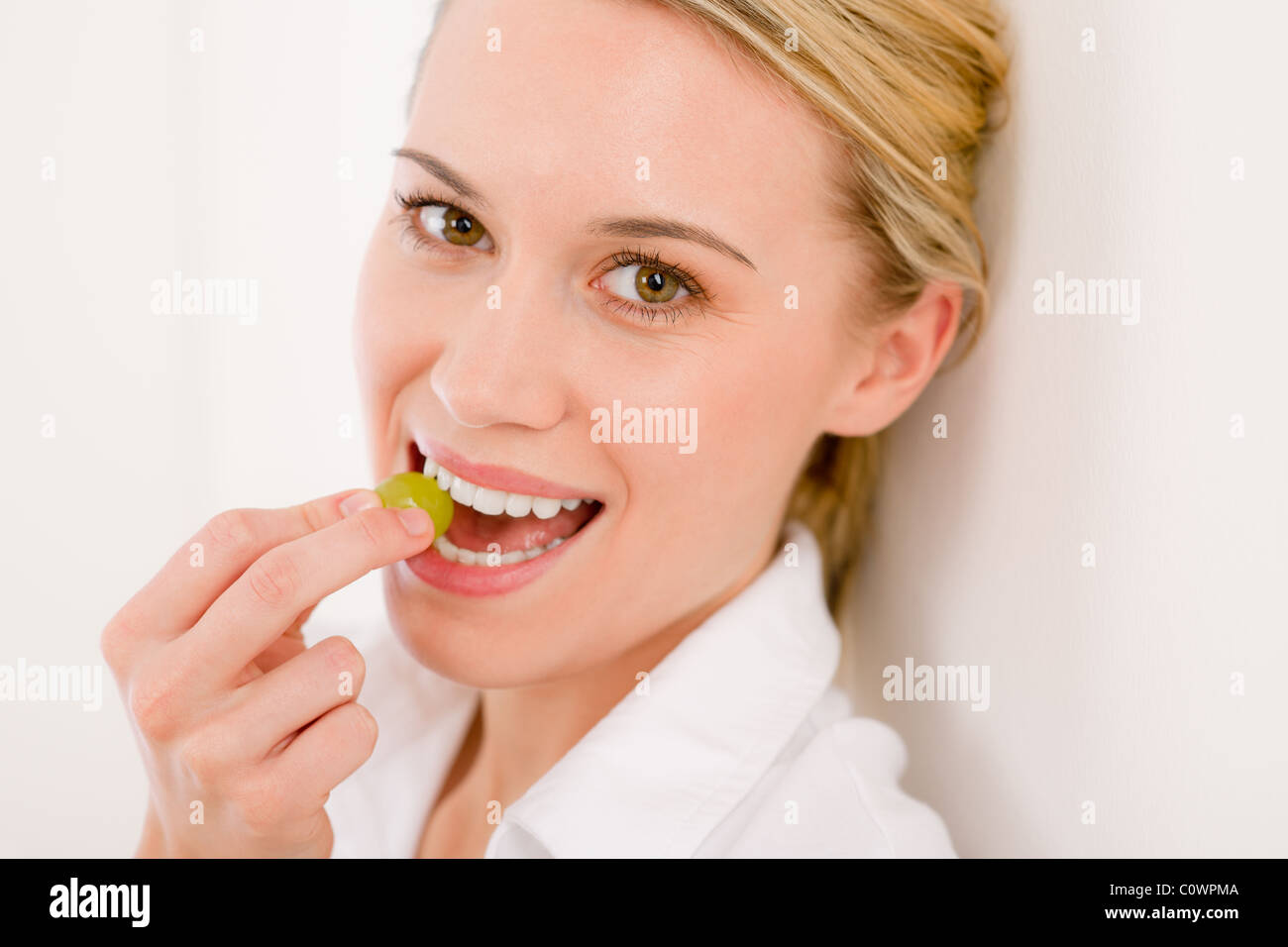 Healthy lifestyle - portrait of woman bite grape on white background ...