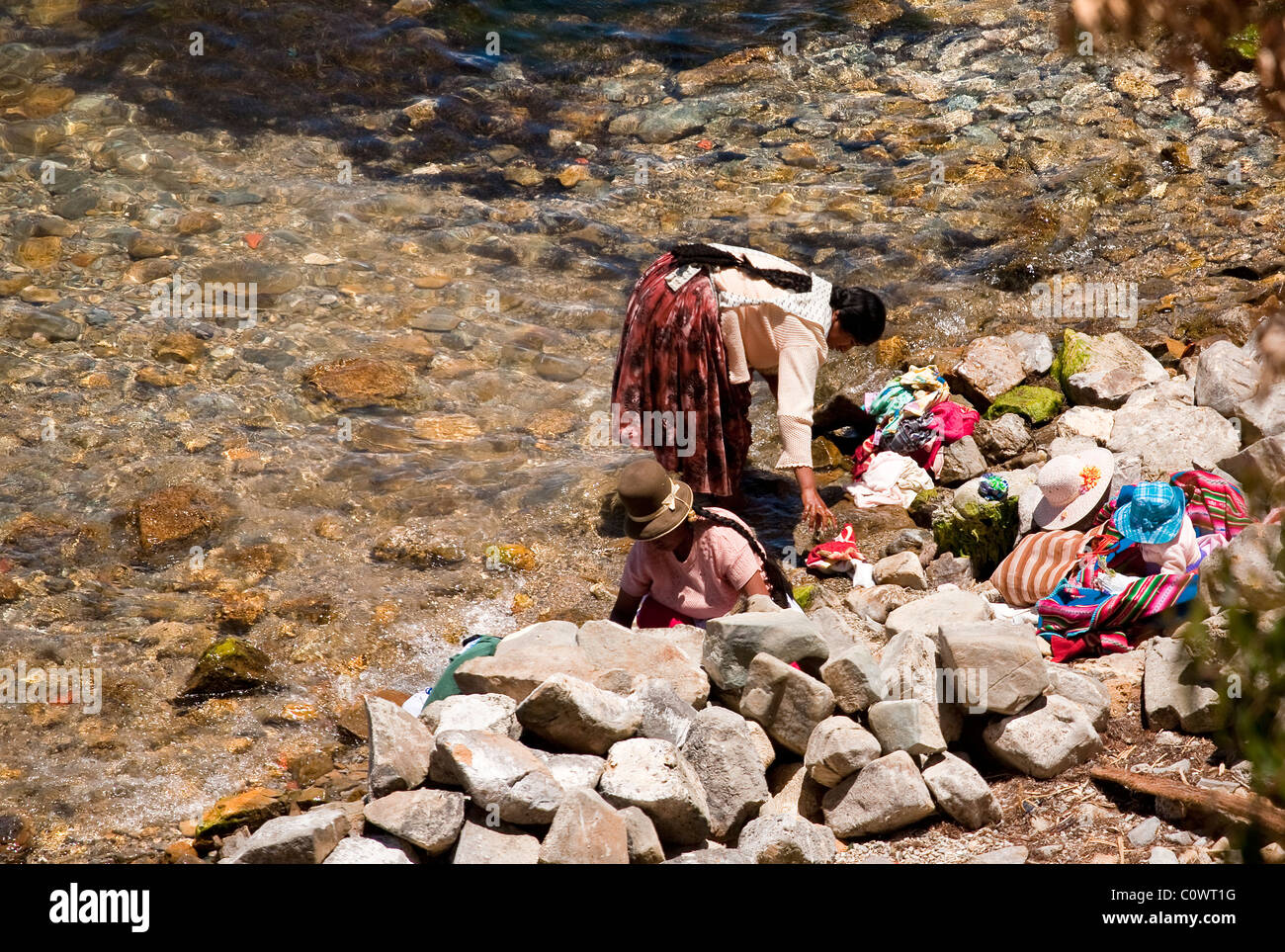 Traditional Bolivian lady washing clothes on the shore of Lake Titicaca ...