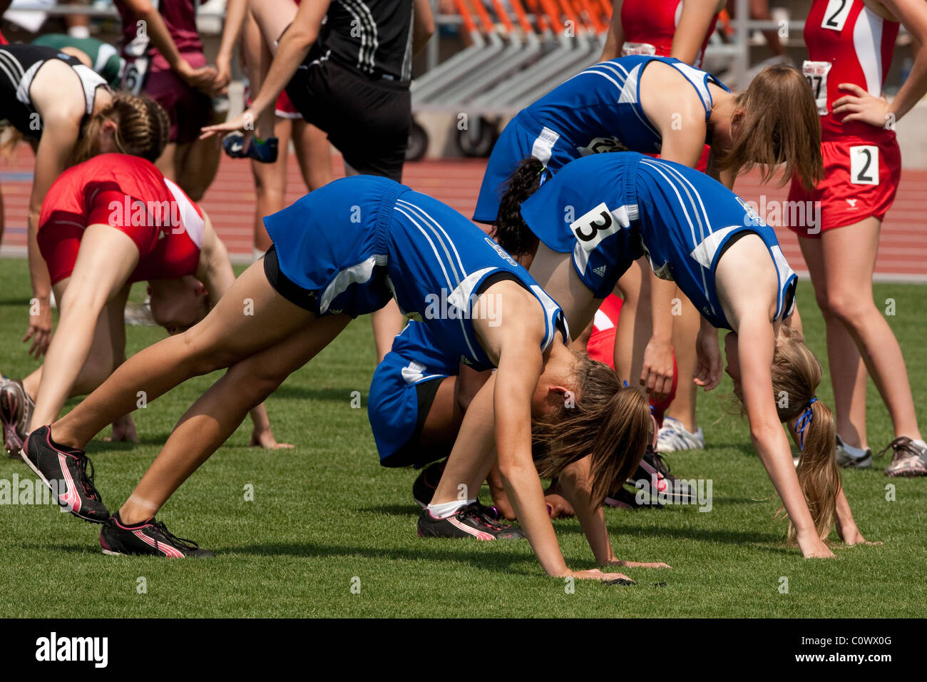 Anglo female track athletes stretch in the infield before their races ...