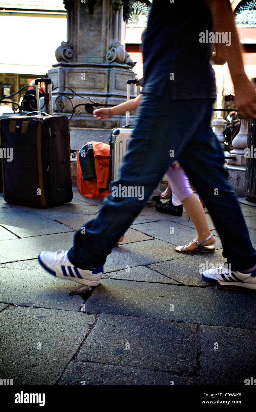 Suitcases in Venice as people walk by in trainers Stock Photo - Alamy