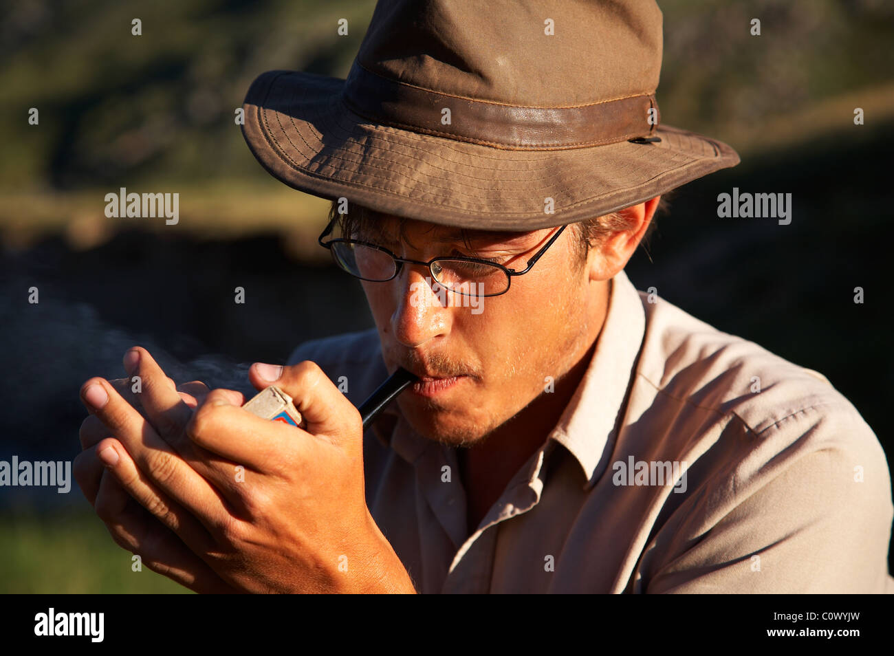 man in hat is smoking tobacco-pipe outdoors Stock Photo - Alamy