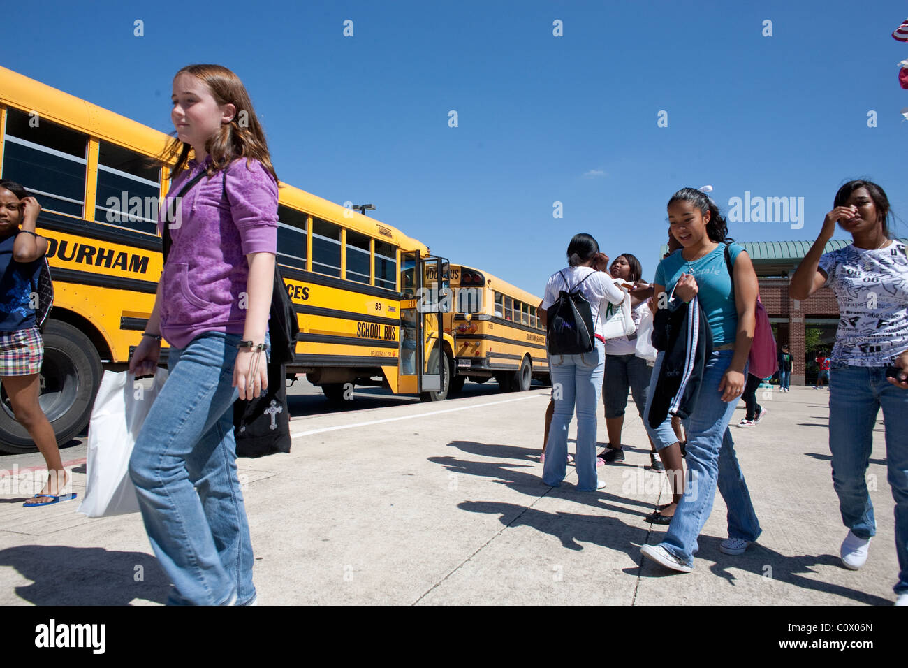 Female students walk to their yellow school buses at the end of the ...