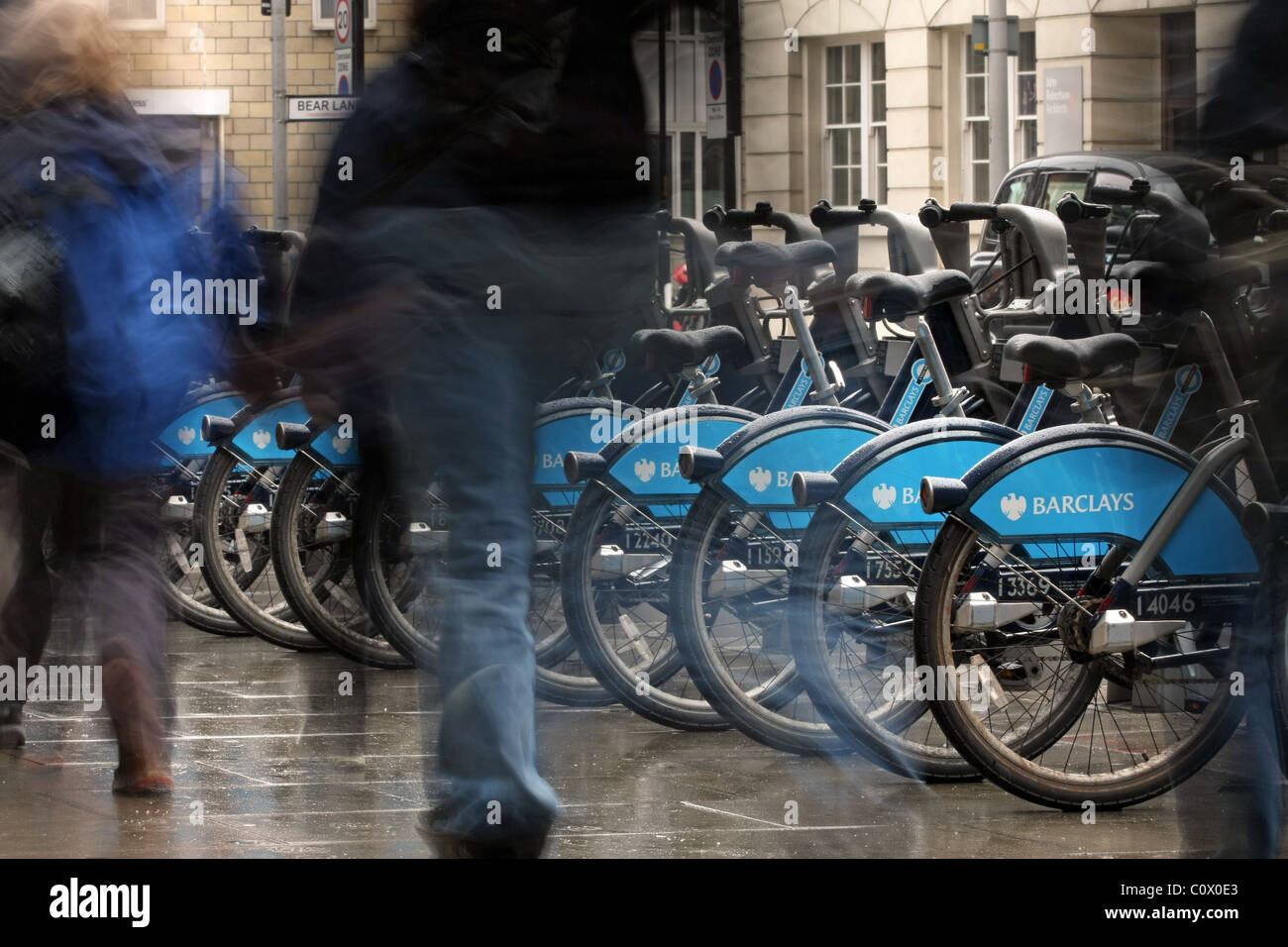 A rack of Boris Bikes with blurred figures walking passed in the ...