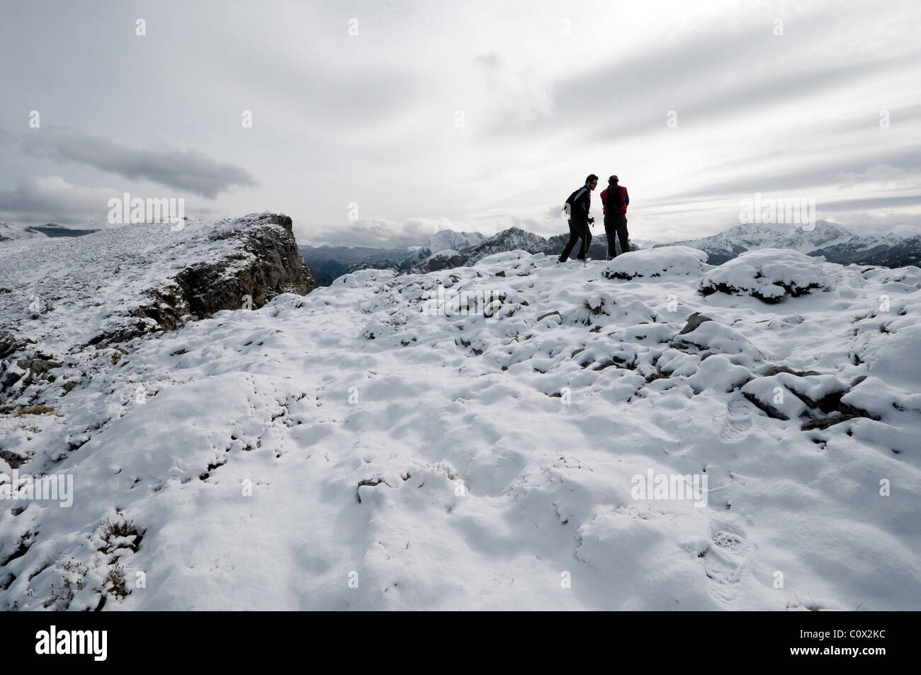 Two hikers walk through the covered in snow mountains of Ponga ...