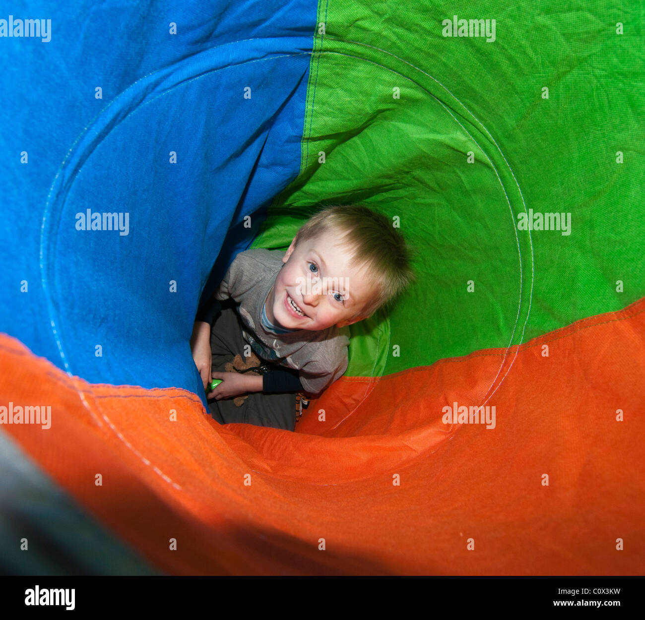 Boy sitting at the bottom of play tunnel Stock Photo - Alamy