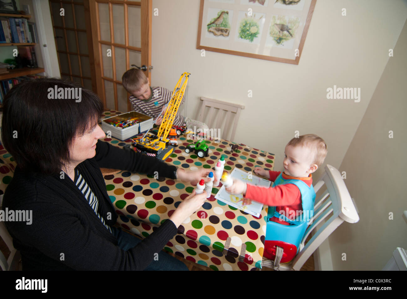 Mother and children playing at dining room table Stock Photo - Alamy