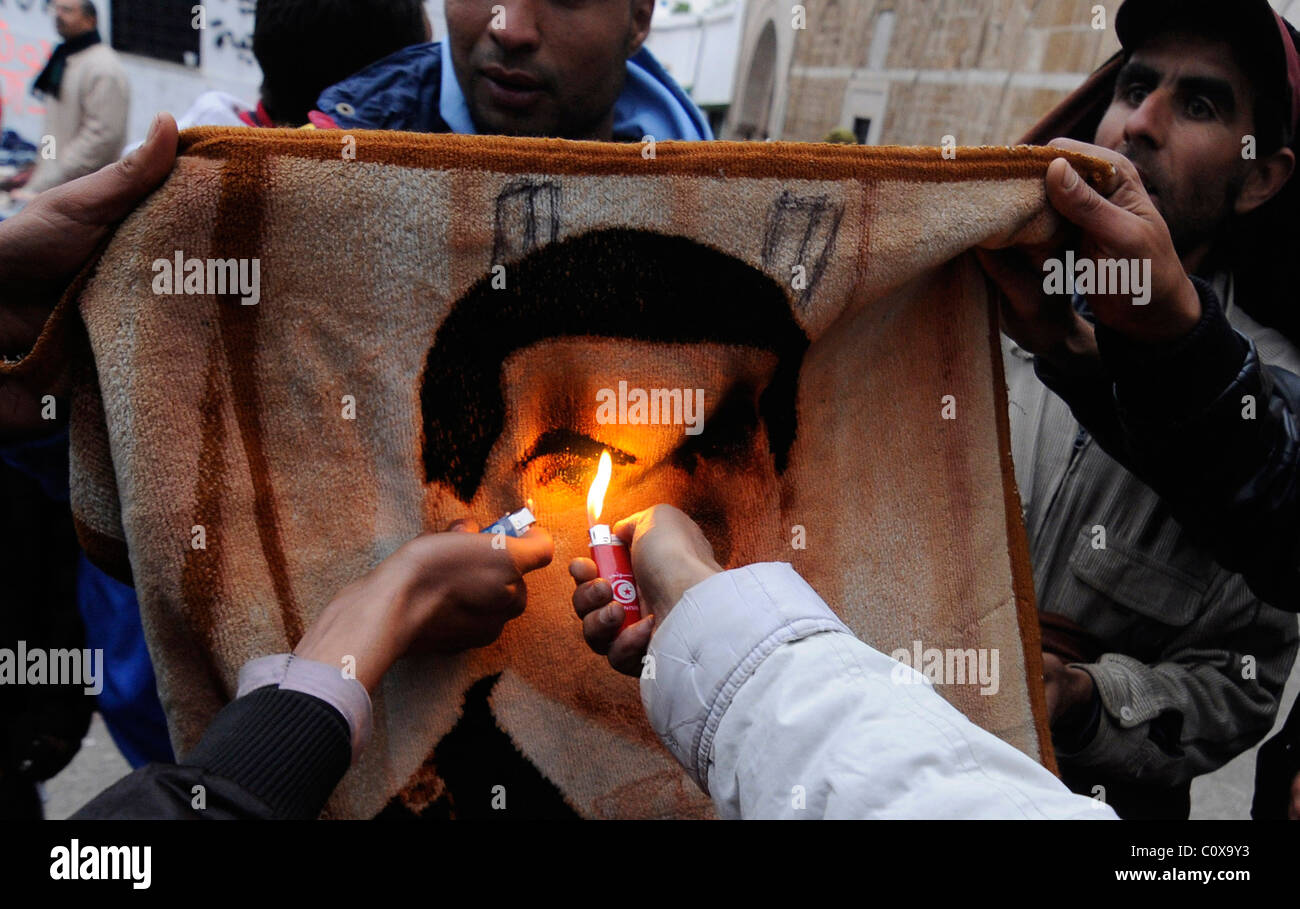 Tunisian people burning a portrait of ousted leader Ben Ali during the ...