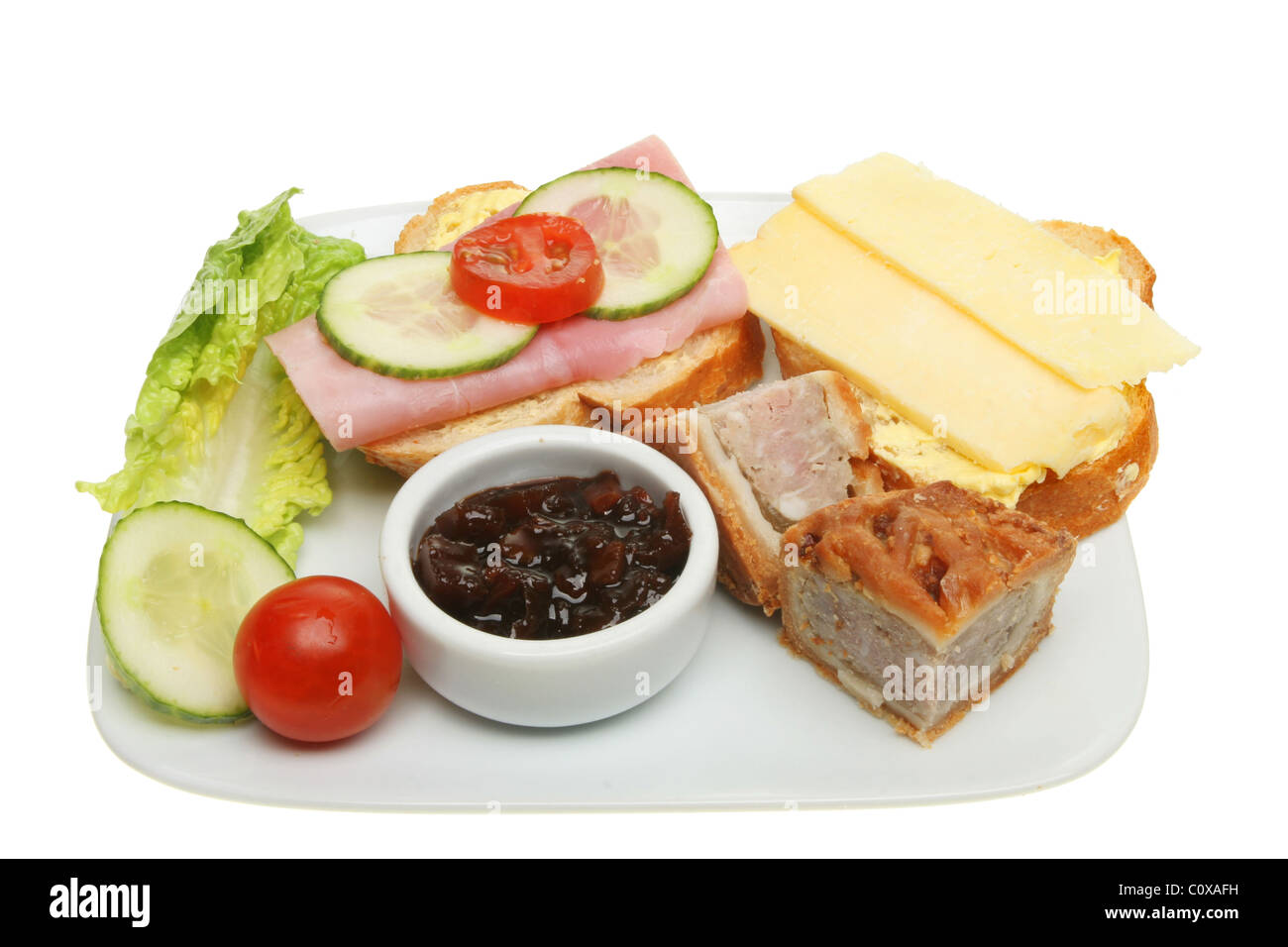 Plate of snack food of pork pie, bread, cheese, ham and salad isolated ...