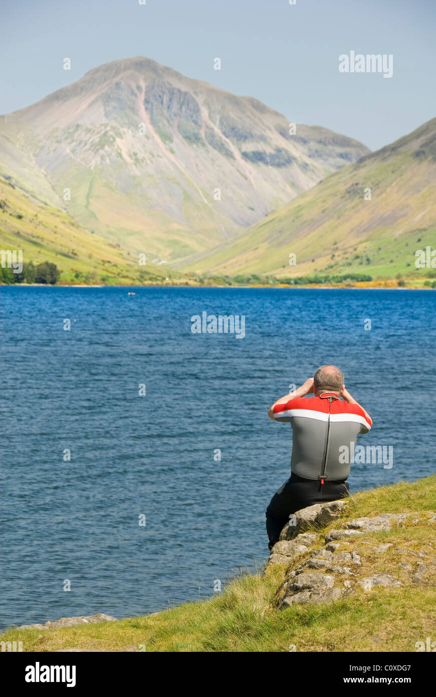 Man sitting on lake shore, looking towards mountain Great Gable ...