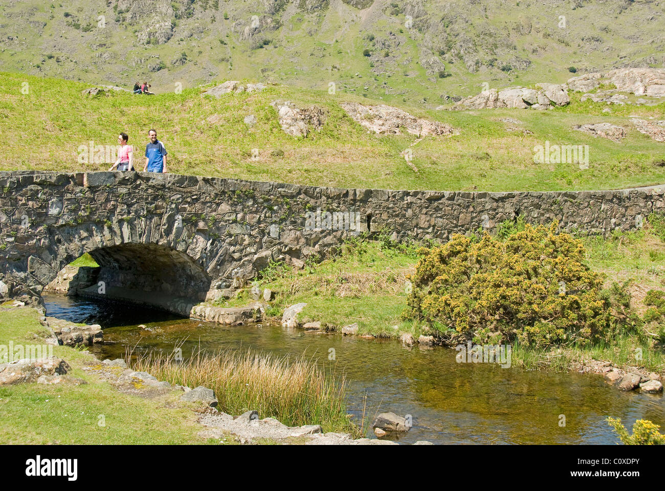 Old stone bridge, people walking over it, Lake District National Park ...