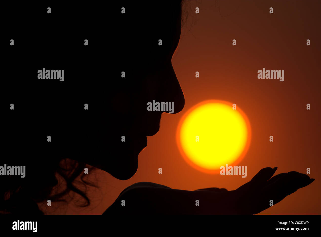 Young female is kissing the Sun during sunrise Stock Photo - Alamy